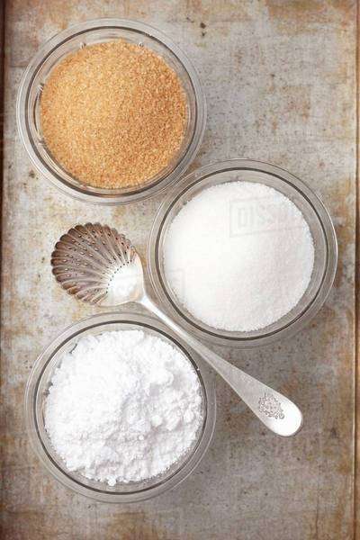 Various types of sugar in glass bowls: white sugar, brown sugar and ...