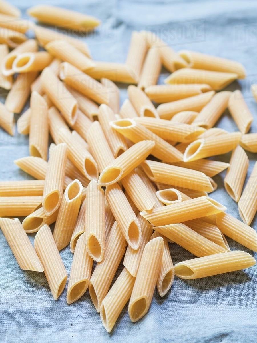 Wholemeal penne pasta on a blue cloth - Royalty-free Stock Photo | Dissolve