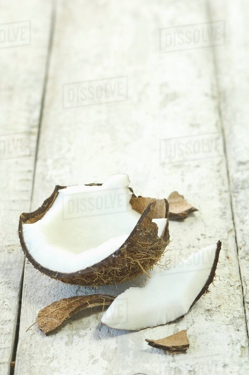 A broken coconut on a wooden surface - Royalty-free Stock Photo | Dissolve