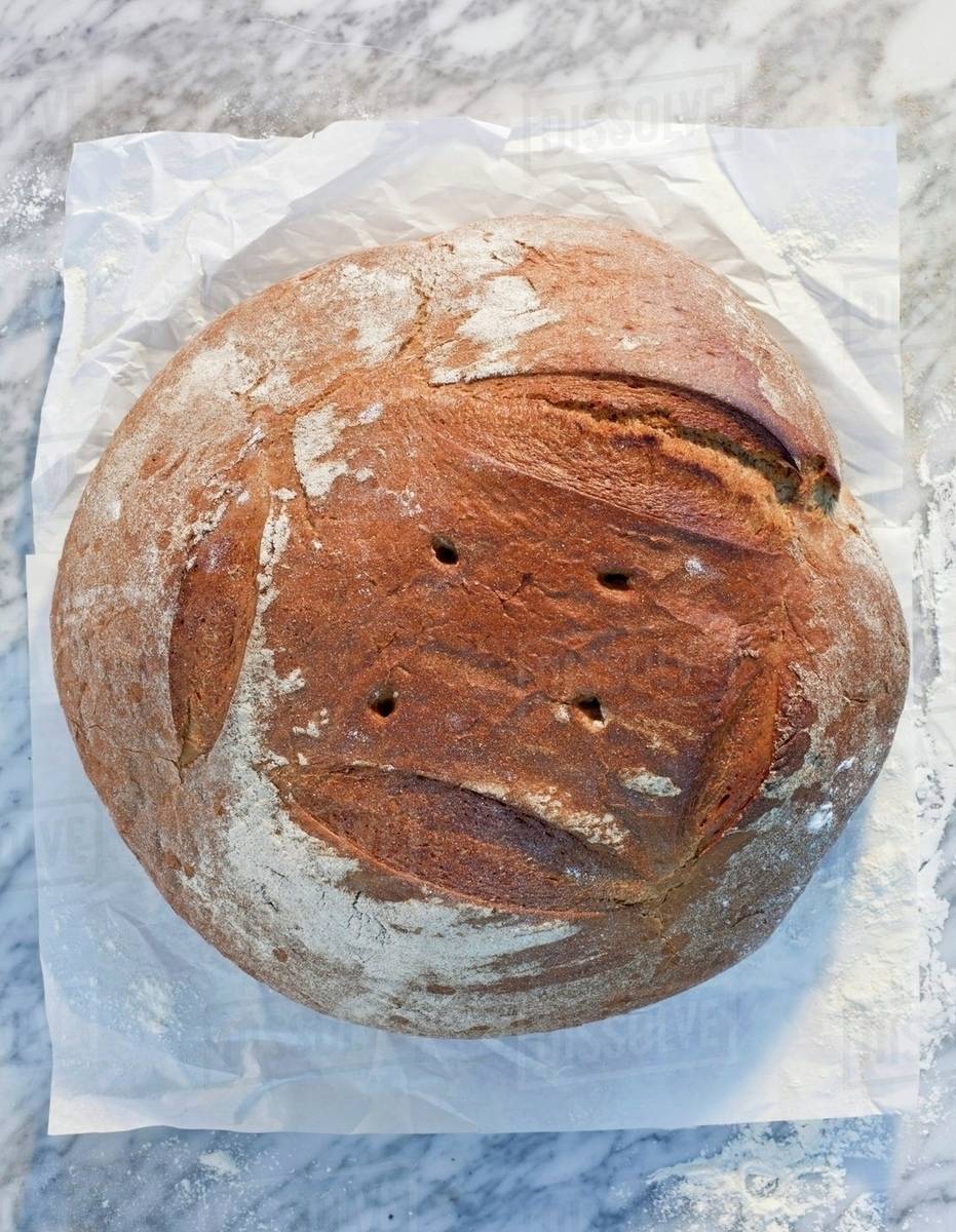 A loaf of bread on paper, on a marble slab, dusted with flour - Royalty ...