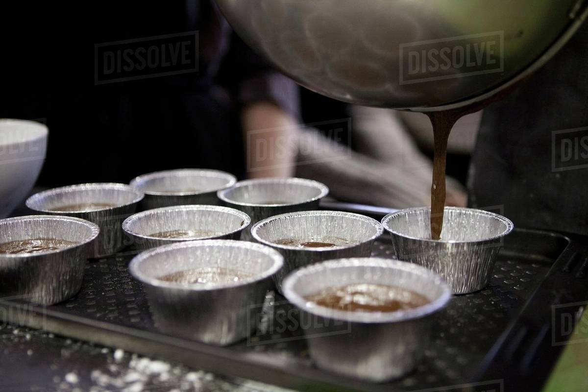 Chocolate mixture being poured into aluminium moulds - Stock Photo ...