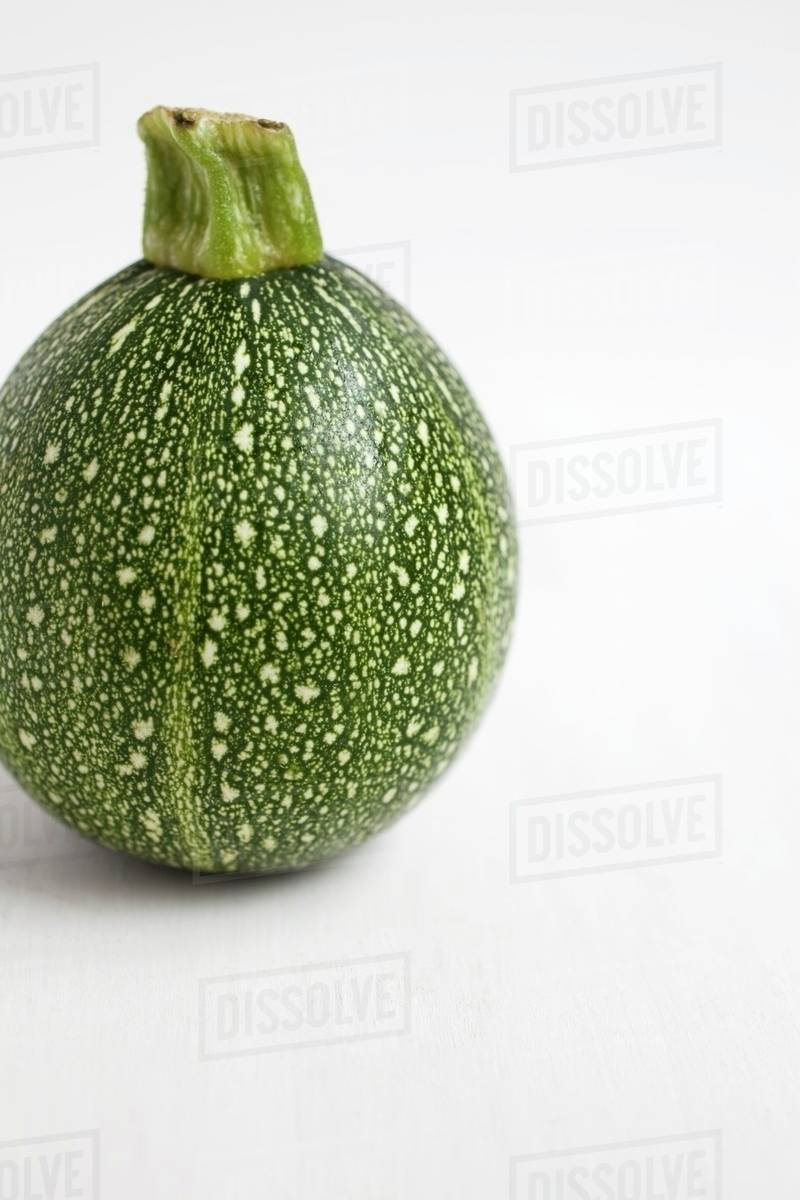 Single spherical courgette against white - Stock Photo - Dissolve