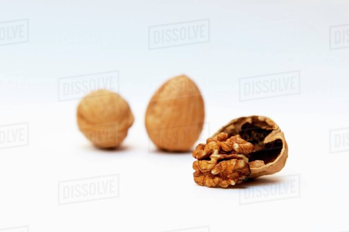 Three walnuts; two whole, one with the shell broken open - Royalty-free ...