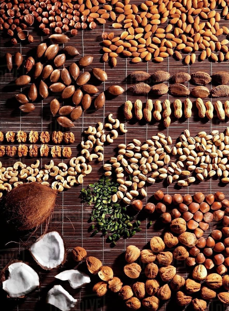 Assorted nuts on a brown raffia mat - Royalty-free Stock Photo | Dissolve
