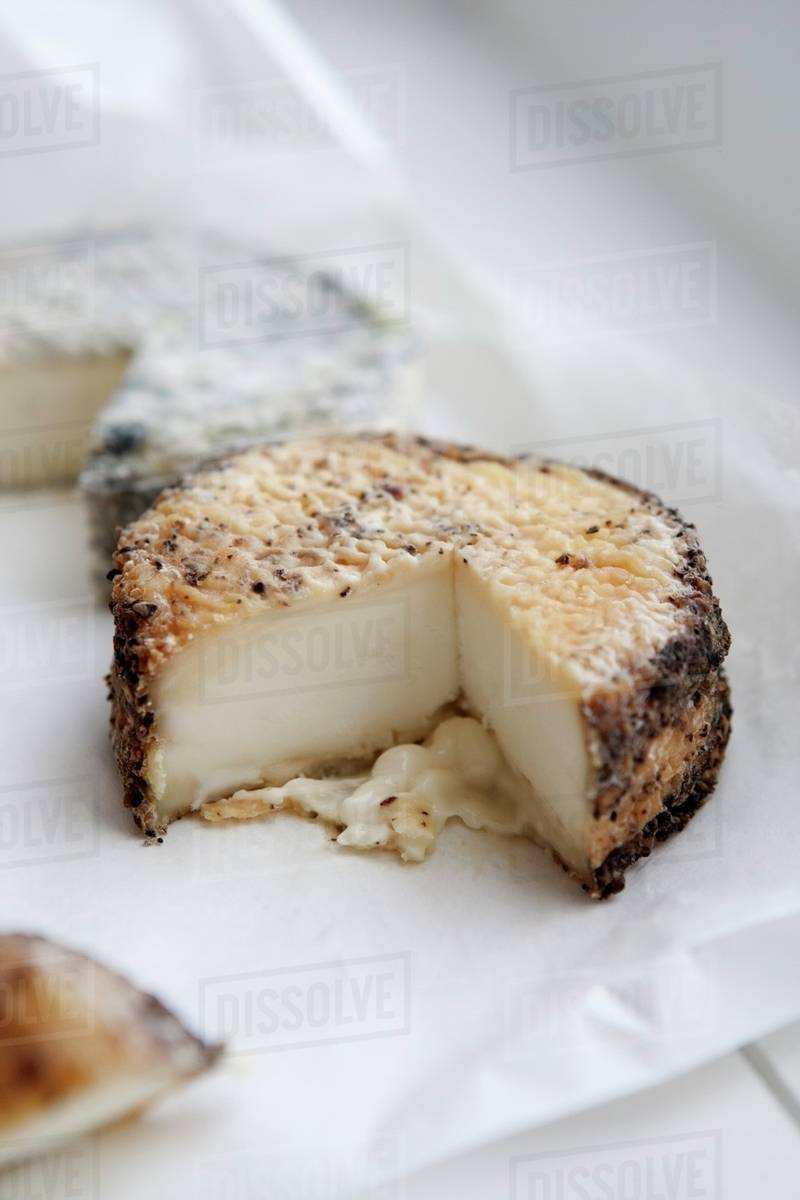 Peppered Aged Goat Cheese Wheel with Wedge Removed - Stock Photo - Dissolve