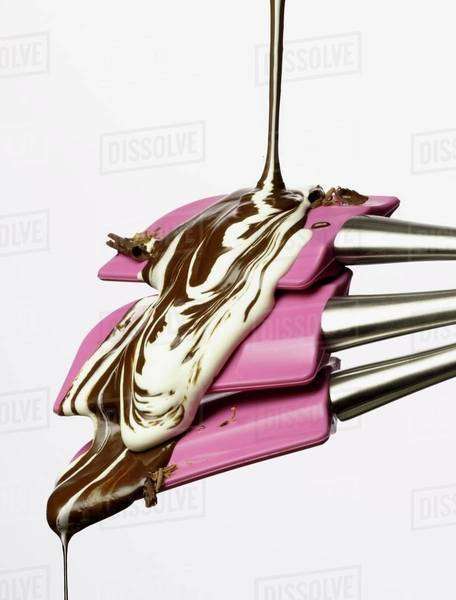 Chocolate sauce flowing over pink coloured spatulas - Stock Photo ...
