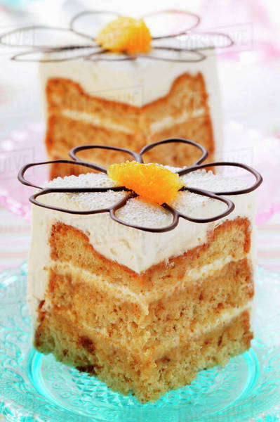 Square of cake with cream icing and chocolate orange flower - Stock ...