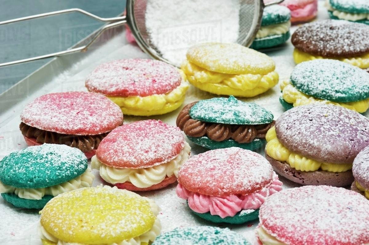 Various macaroons dusted with icing sugar on a baking tray - Royalty ...
