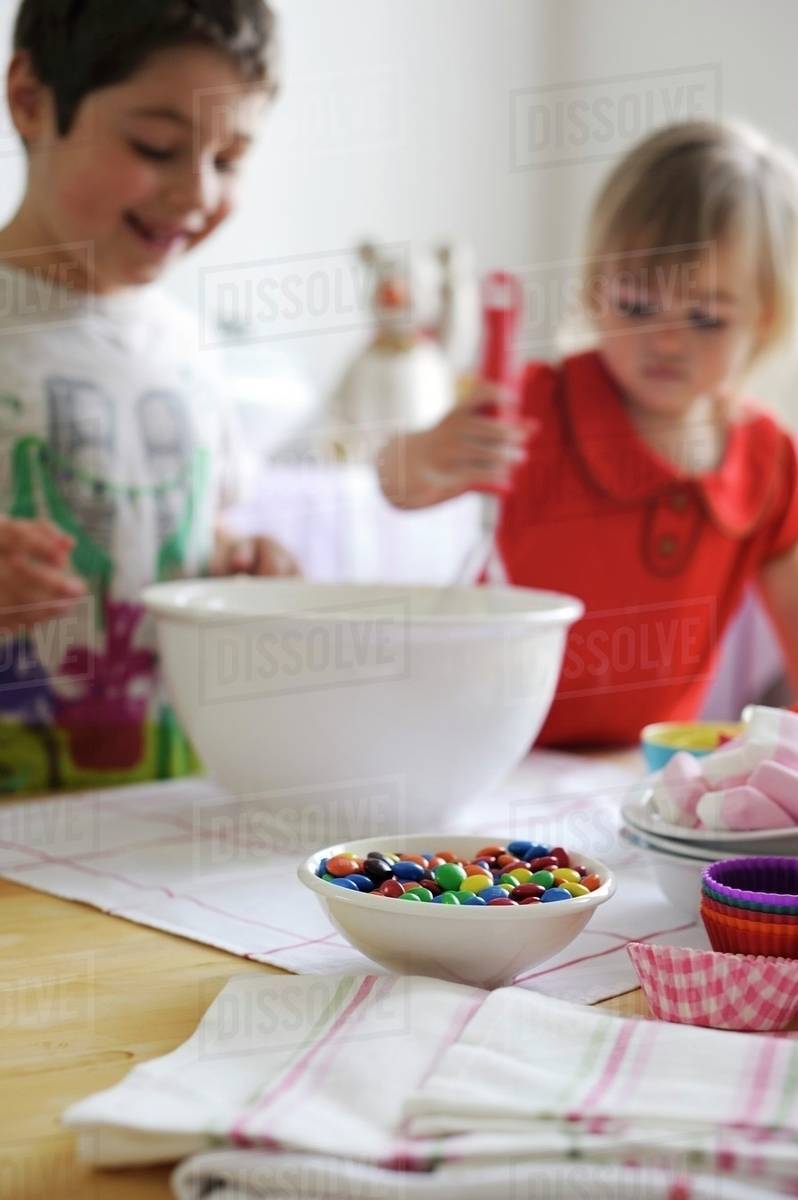 Young boy and girl mixing ingredients for cupcakes in a bowl - Royalty ...
