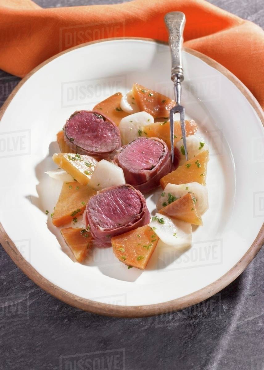 Saddle of lamb wrapped in bacon with yellow and white turnips - Stock ...