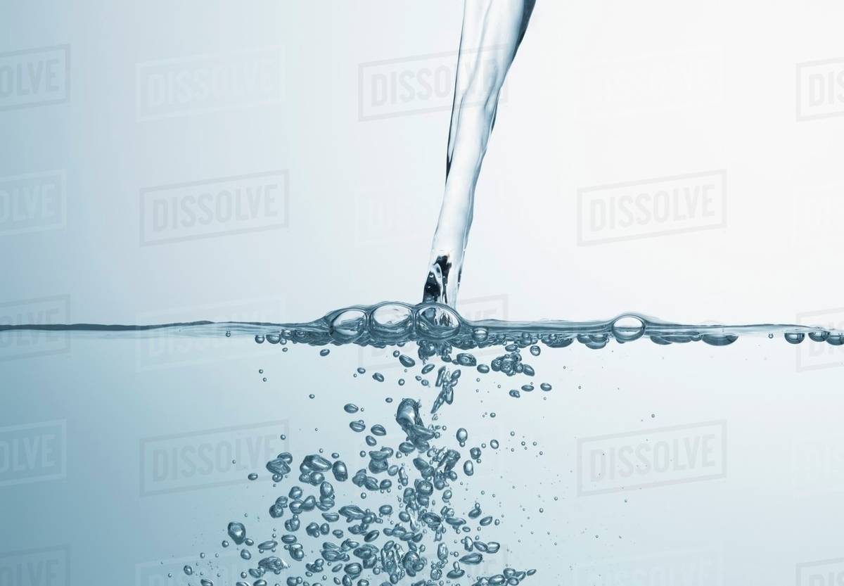 Stream of water hitting surface of water - Stock Photo - Dissolve