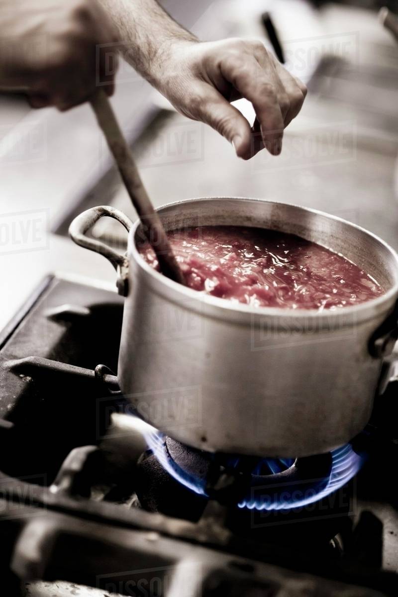 A cook seasoning tomato sauce with salt - Stock Photo - Dissolve