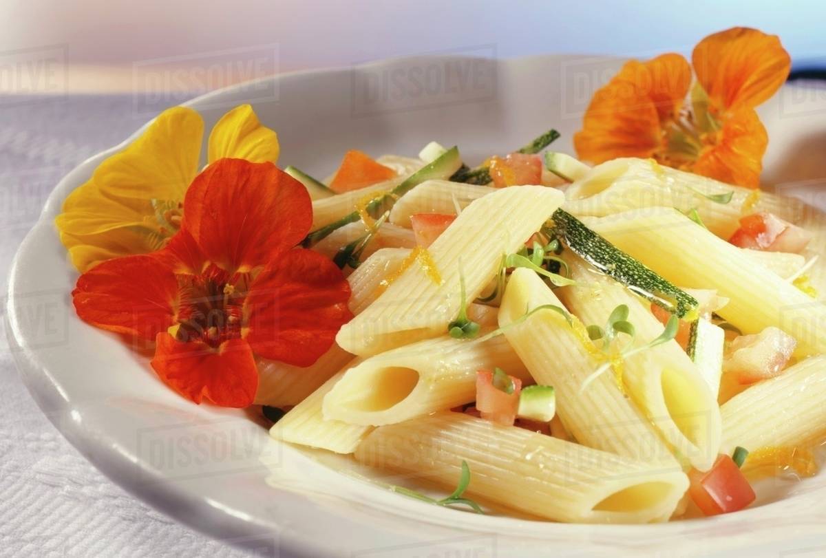 Penne with vegetables and nasturtium flowers - Stock Photo - Dissolve