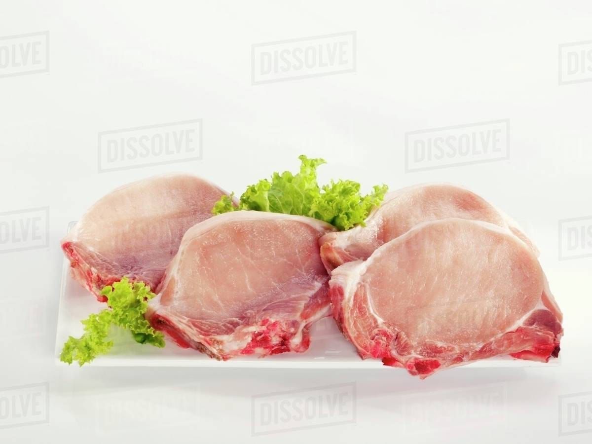 Four pork chops on a serving platter - Stock Photo - Dissolve