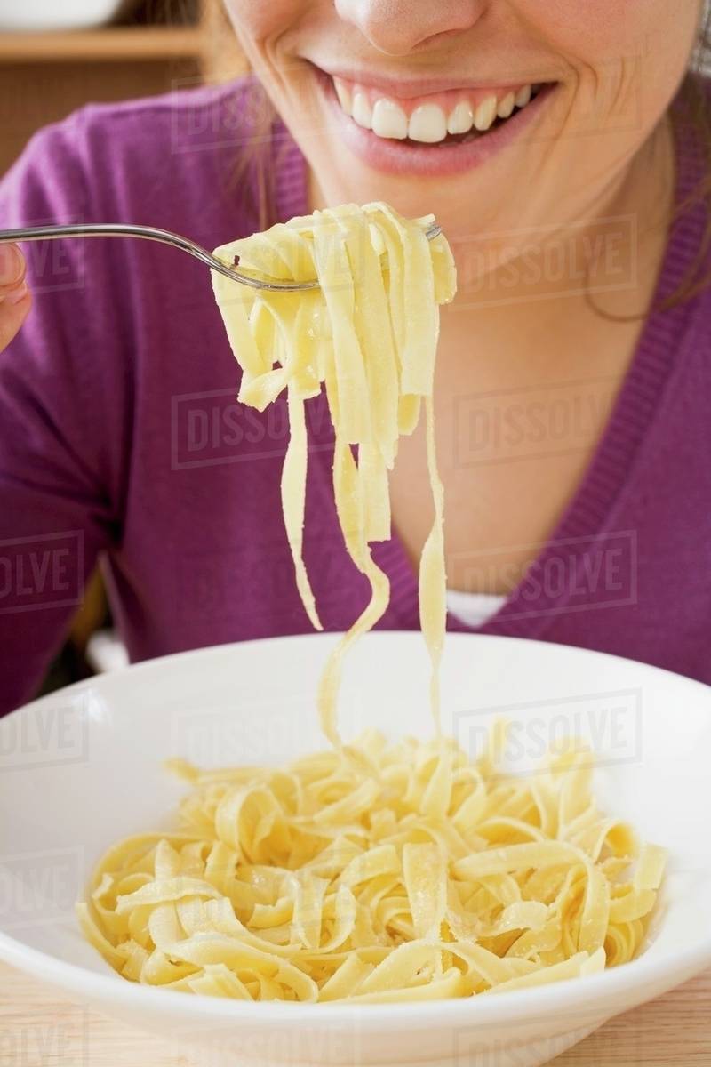 Woman eating ribbon pasta - Stock Photo - Dissolve