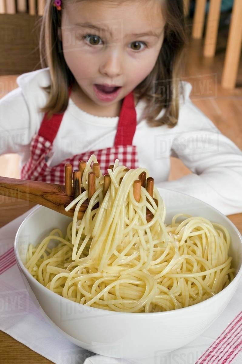 Small girl sitting in front of a bowl of cooked spaghetti - Royalty ...