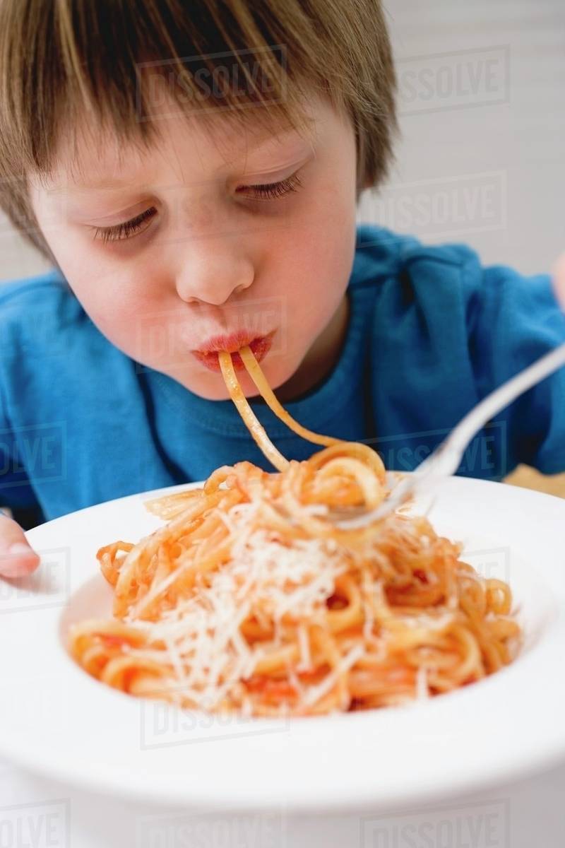 Small boy eating spaghetti with tomato sauce - Stock Photo - Dissolve
