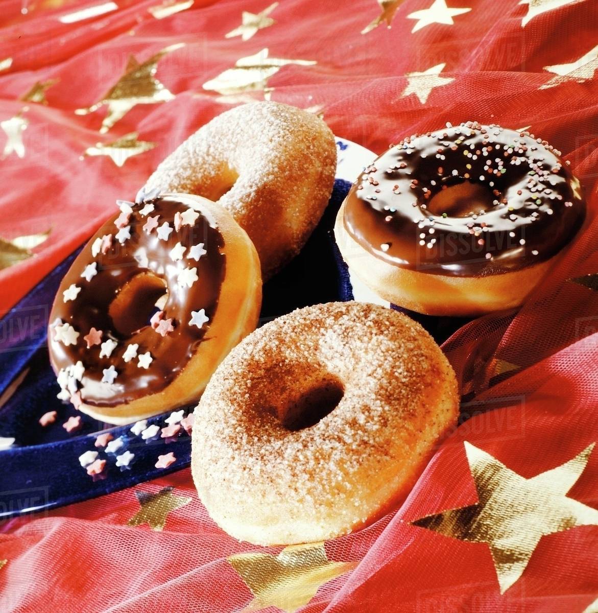 Four doughnuts on a star-patterned cloth - Stock Photo - Dissolve