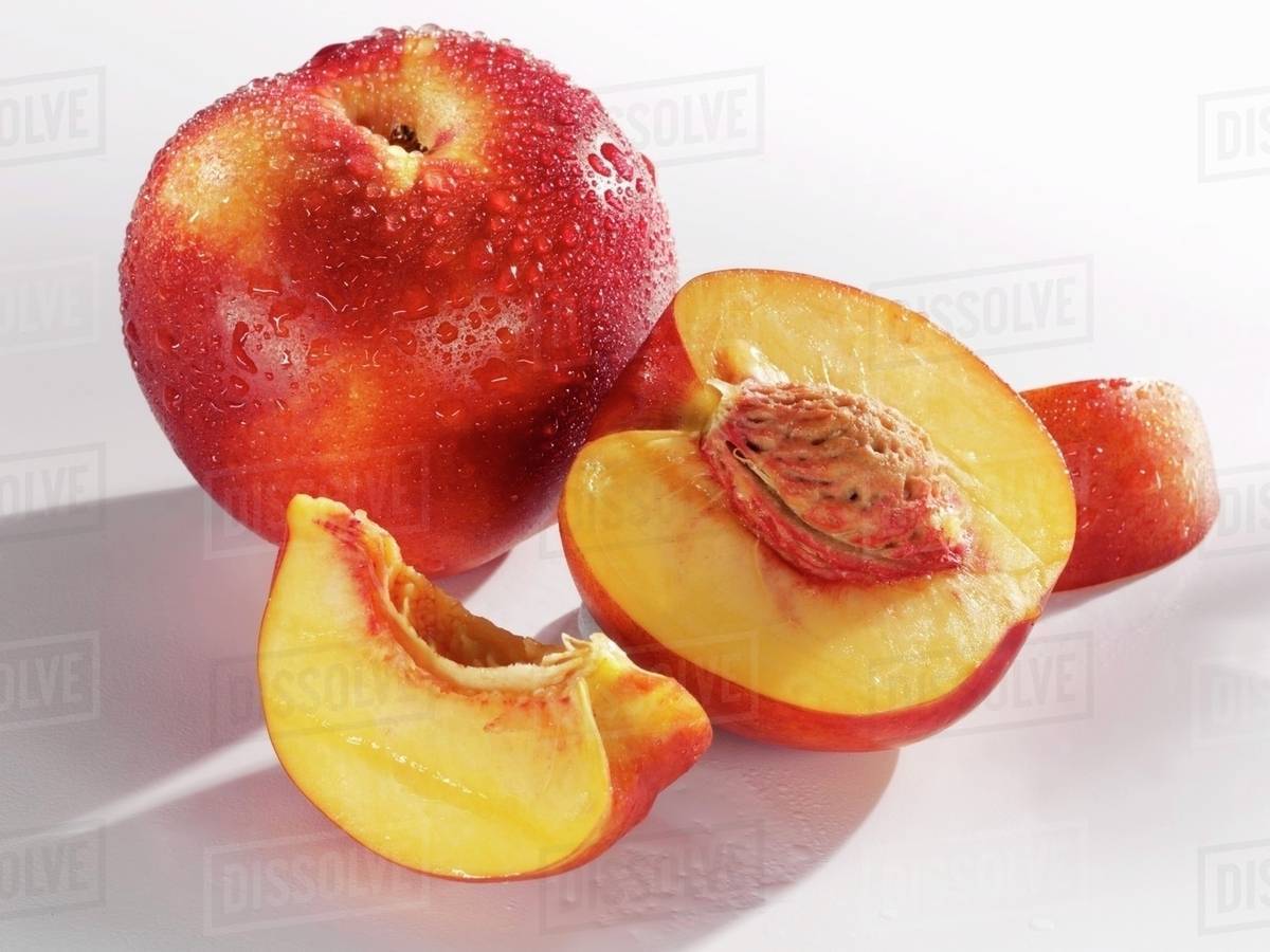 A whole nectarine and one cut into pieces - Stock Photo - Dissolve