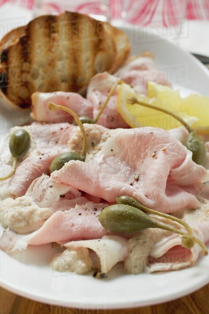 Cold roast pork with capers, lemon and toasted bread - Stock Photo ...
