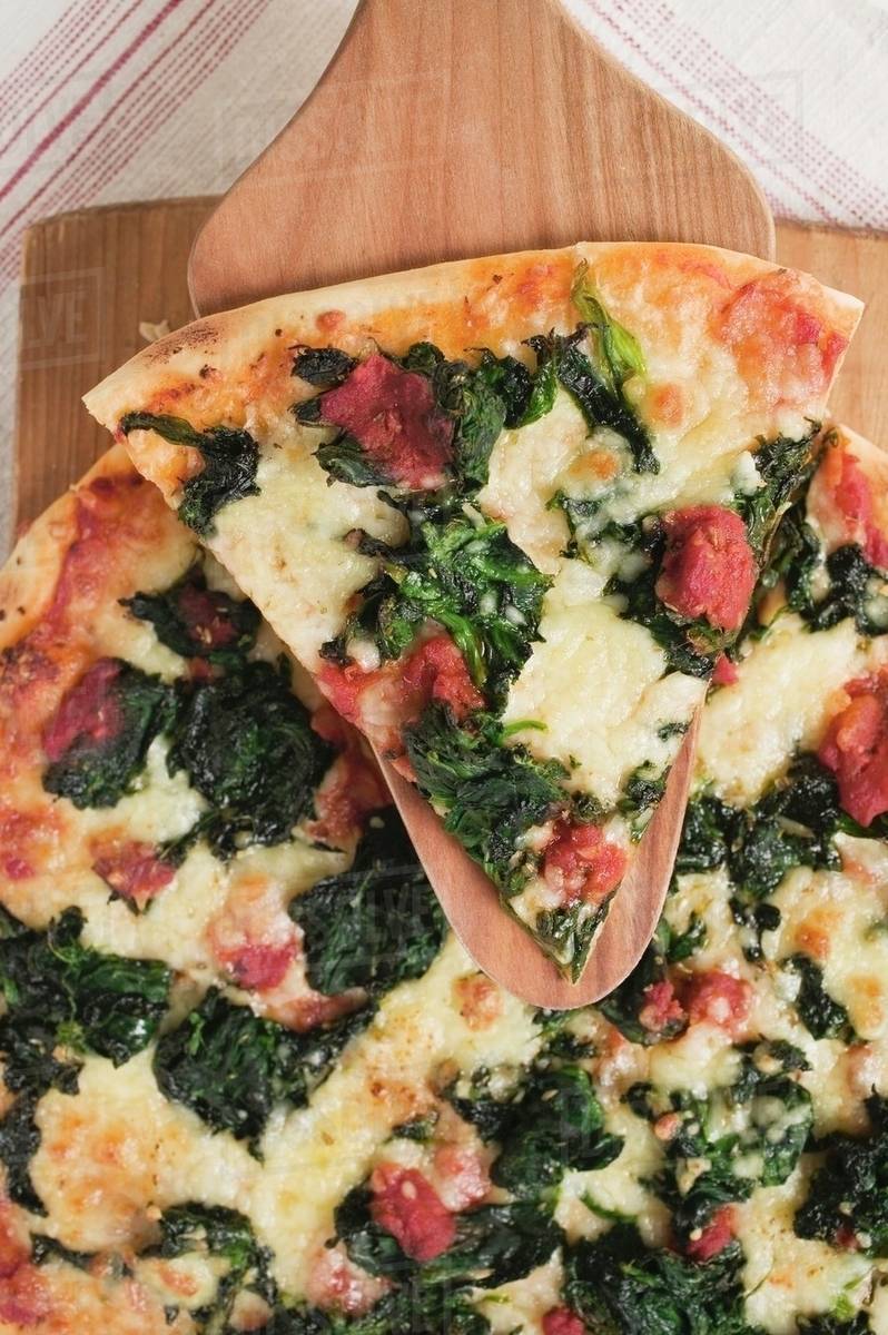 Spinach, tomato and cheese pizza with slice on server - Royalty-free ...