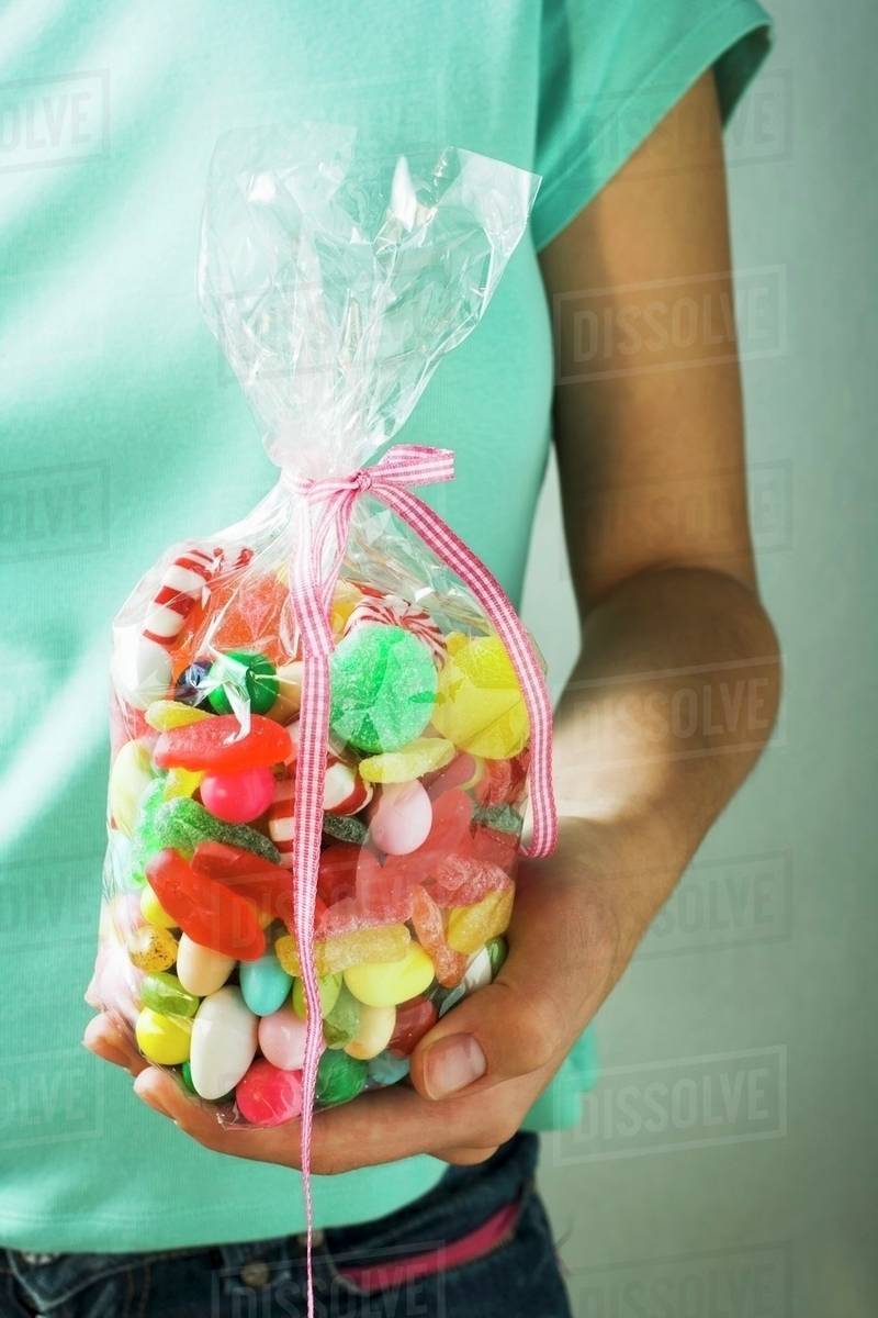 Hand holding cellophane bag of coloured sweets - Royalty-free Stock ...