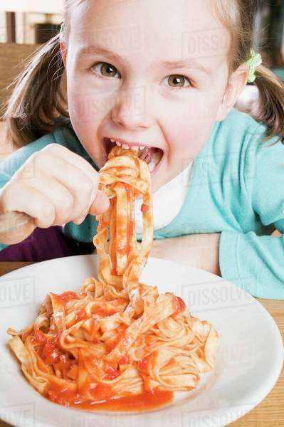Girl eating ribbon pasta with tomato sauce - Royalty-free Stock Photo ...