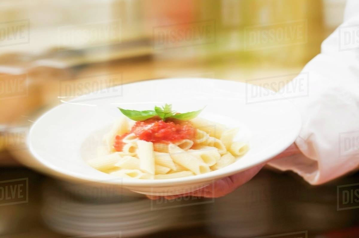 Chef serving penne with tomato sauce - Royalty-free Stock Photo | Dissolve
