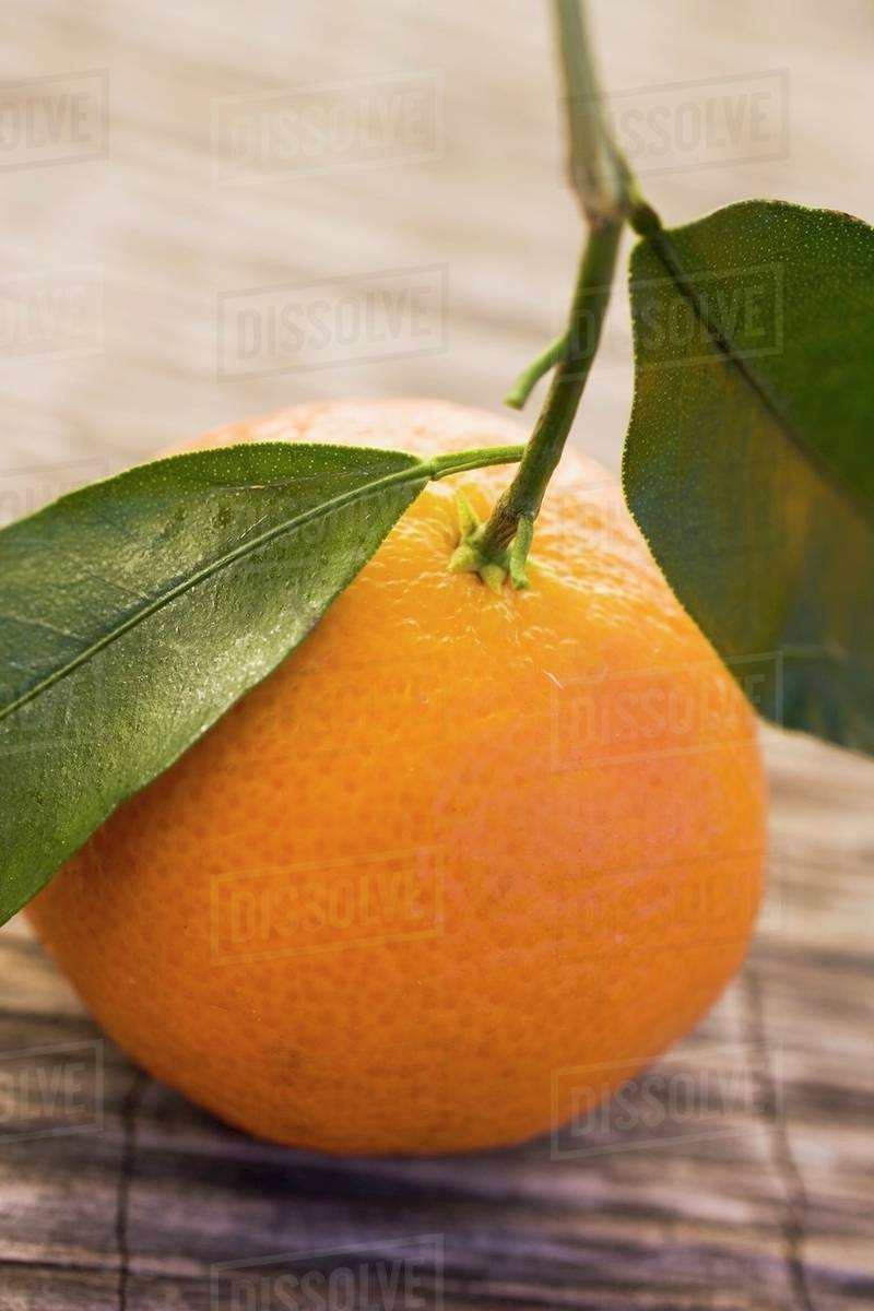 Clementine with leaves on wooden background (close-up) - Stock Photo ...