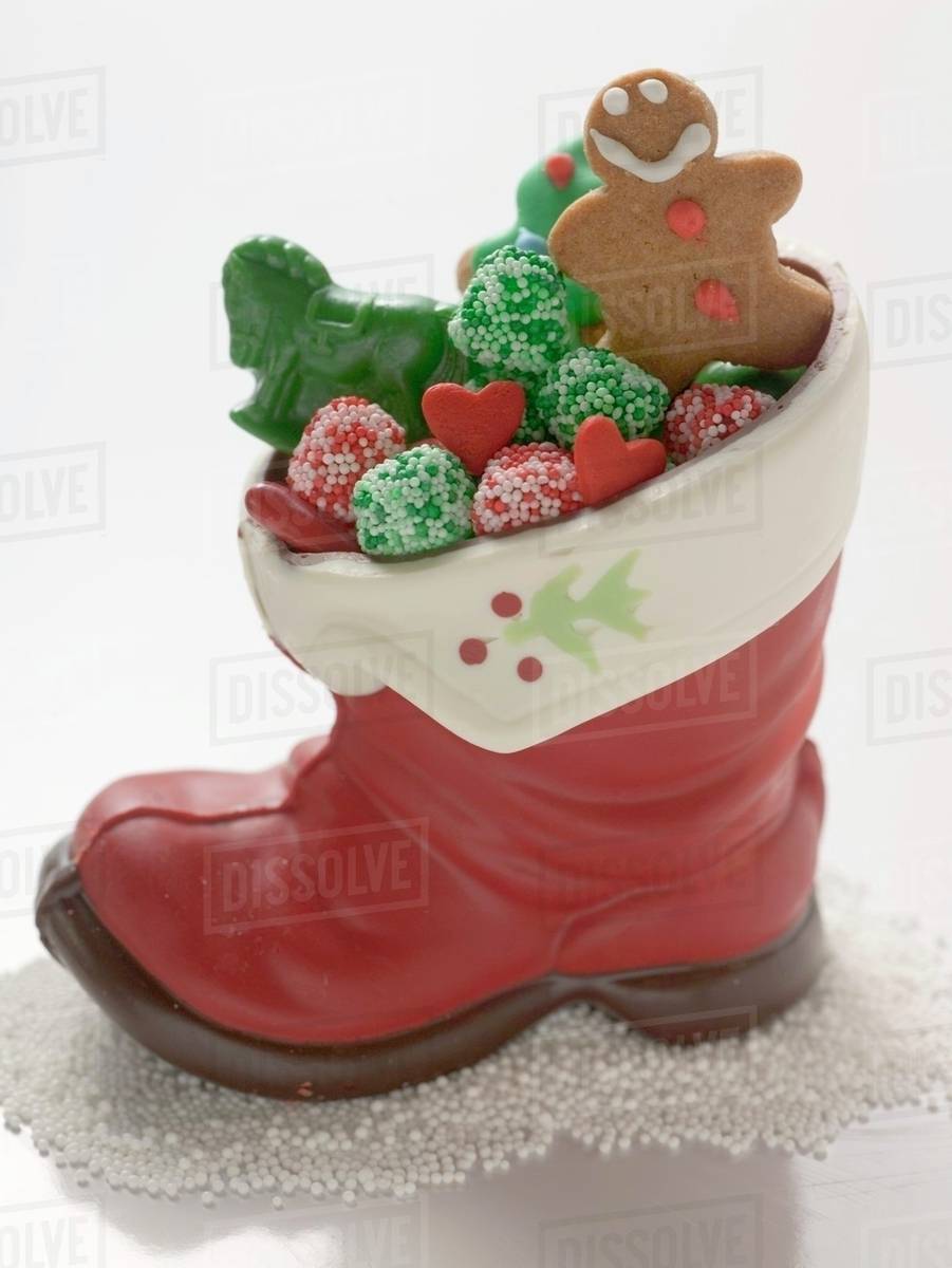 Christmas biscuits and sweets in chocolate boot - Stock Photo - Dissolve