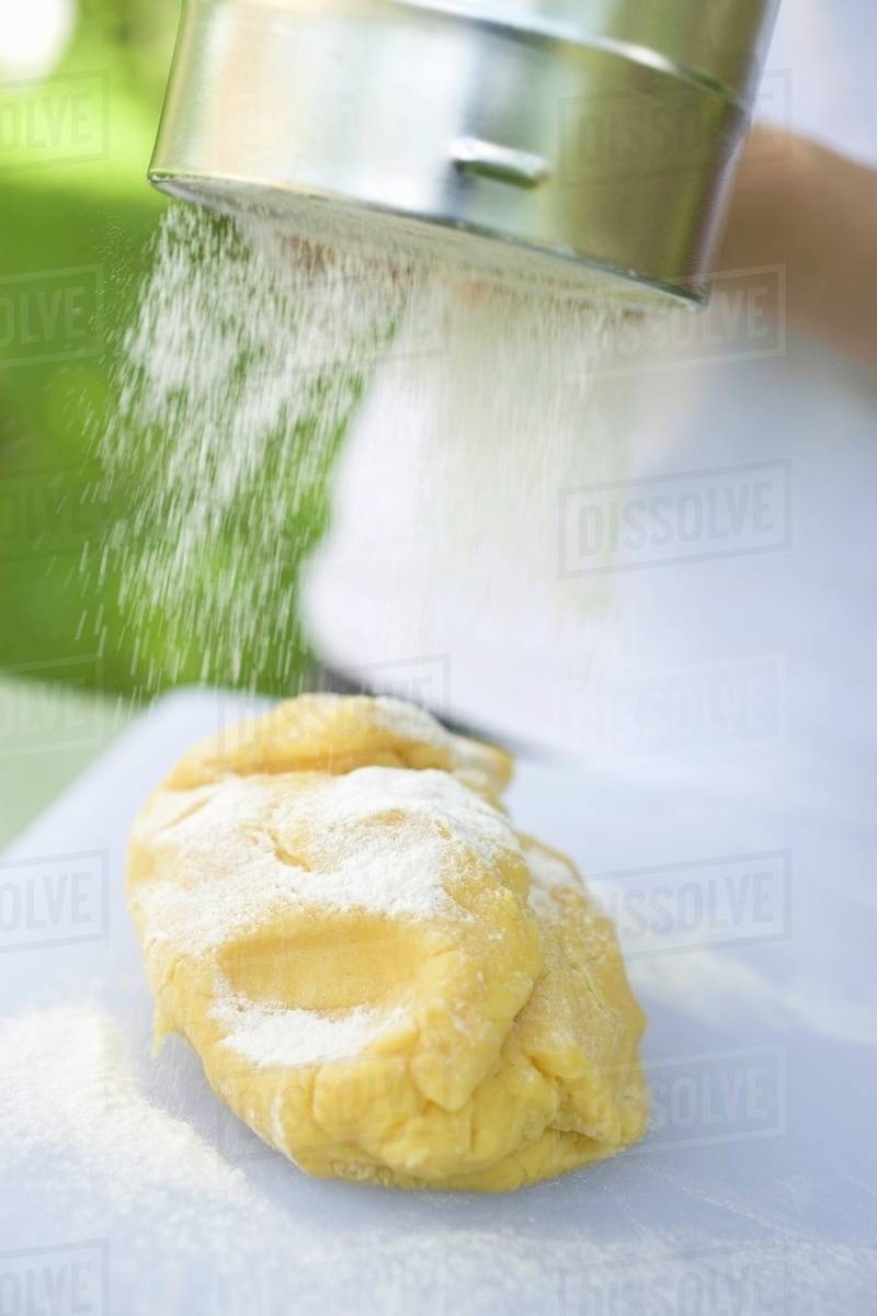 Sprinkling dough with sifted flour - Stock Photo - Dissolve
