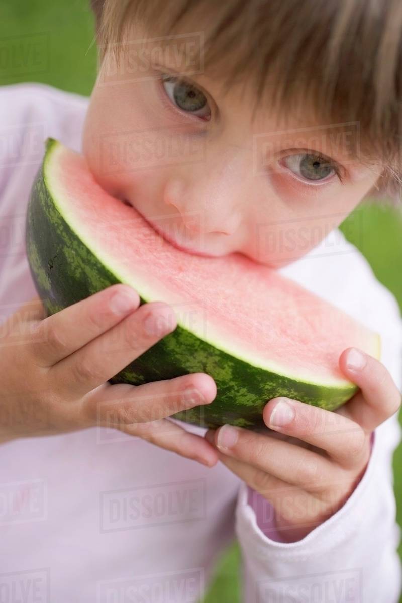 Child biting into watermelon - Stock Photo - Dissolve