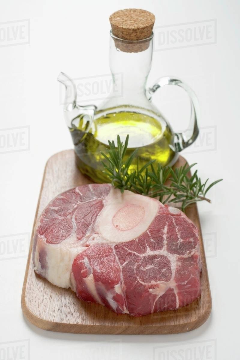 Slice of beef from the leg on chopping board, rosemary, olive oil ...