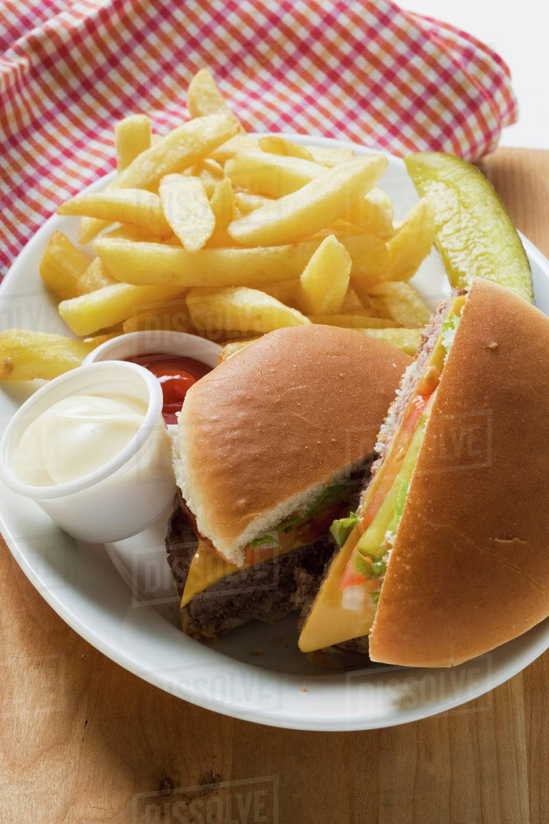Cheeseburger, chips, mayonnaise, ketchup on plate - Stock Photo - Dissolve