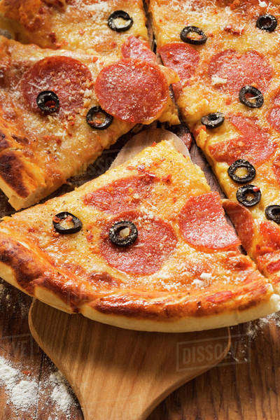 Pizza with salami, cheese and olives, pieces cut - Stock Photo - Dissolve