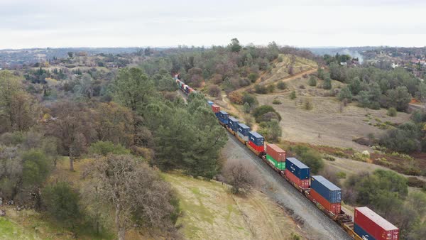 Aerial shot of a freight train on railroad track loaded with cargo ...