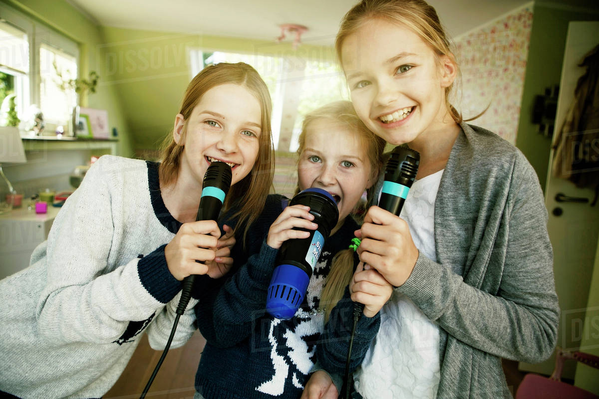Three girls singing with microphone - Stock Photo - Dissolve
