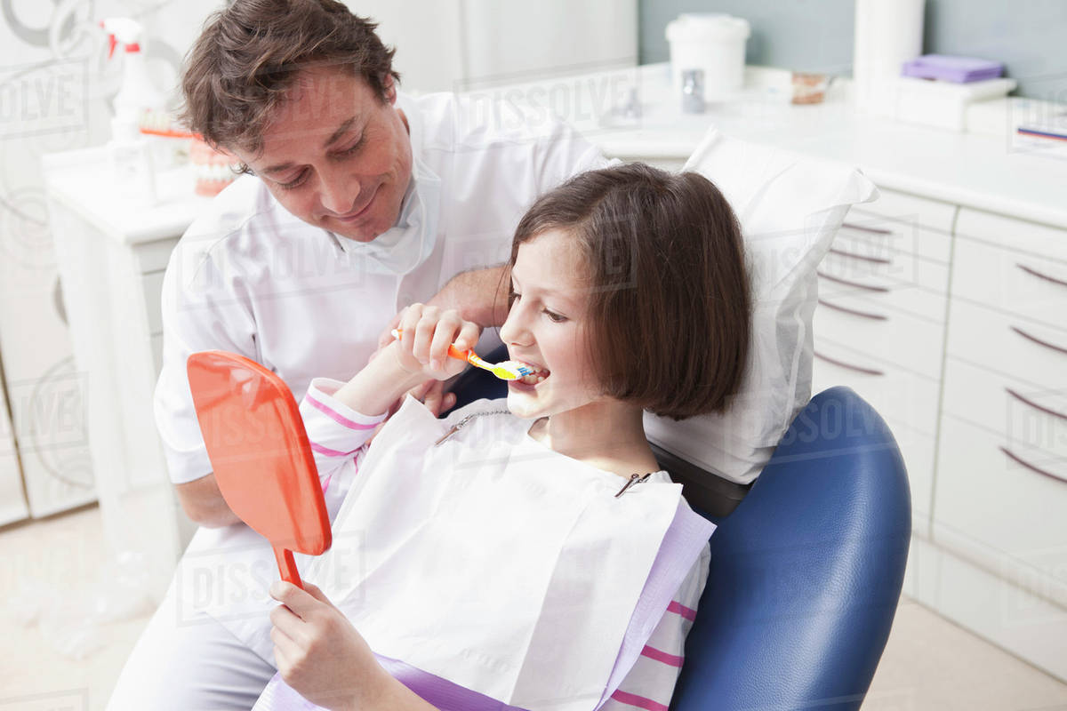Germany, Bavaria, Patient brushing teeth while doctor looking at her ...