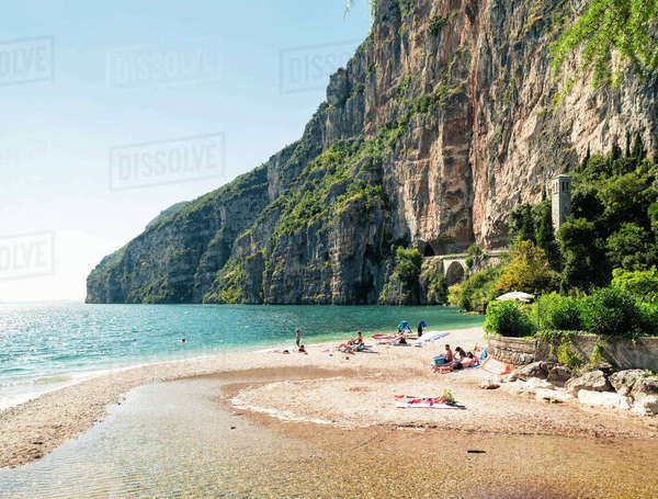 Italy, Lake Garda, People sunbathing at beach at Lido di Tignale ...