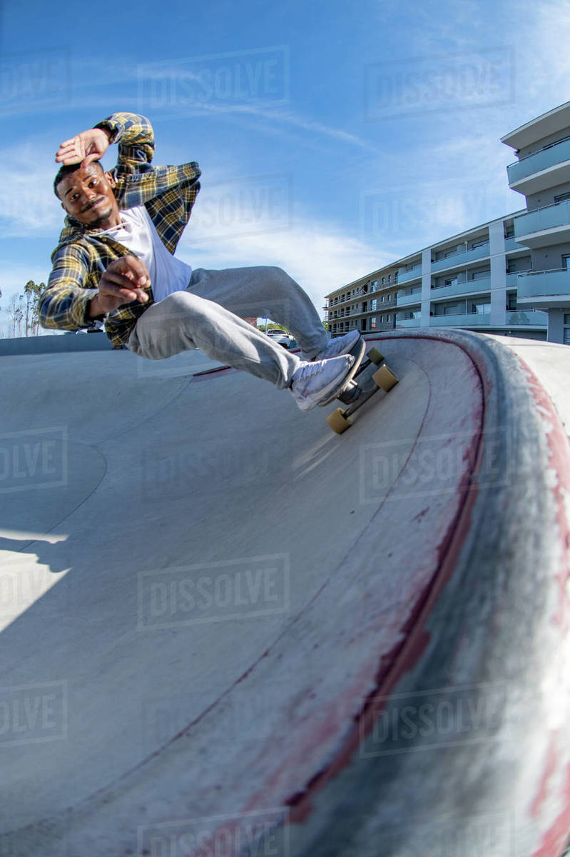 Surf skater performing a high speed turn on a skatepark during a sunny ...