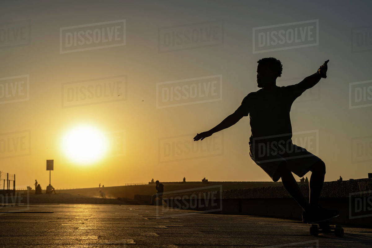 Surf skater training surfing moves near the beach at sunset. - Stock ...