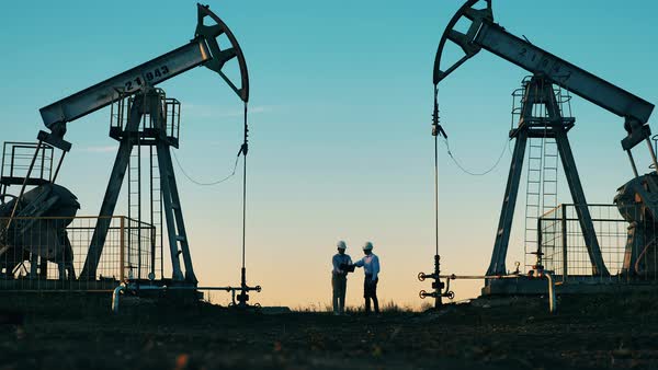 Technicians are talking between two oil pumping units. Oil well, crude ...