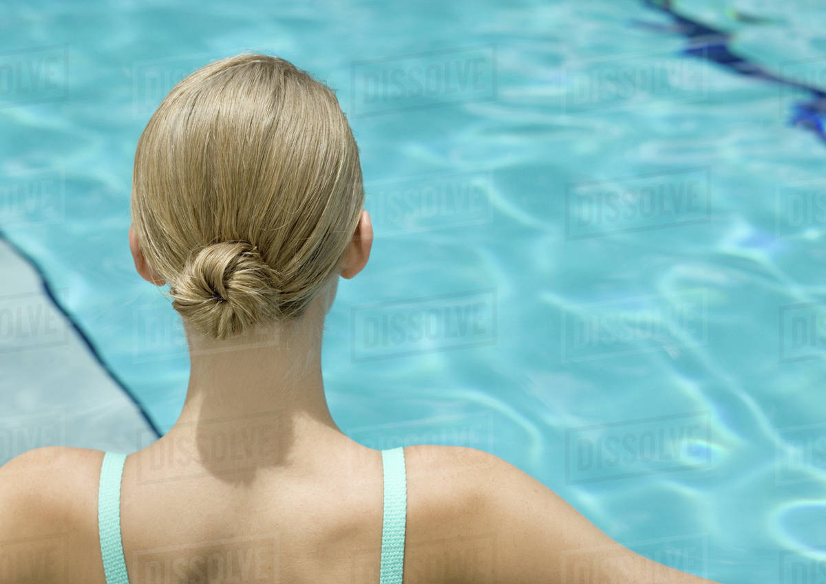 Young woman, rear view of head and shoulders, pool in background ...