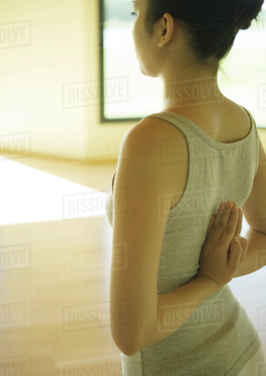 Yoga class, woman standing with hands clasped behind back - Royalty ...