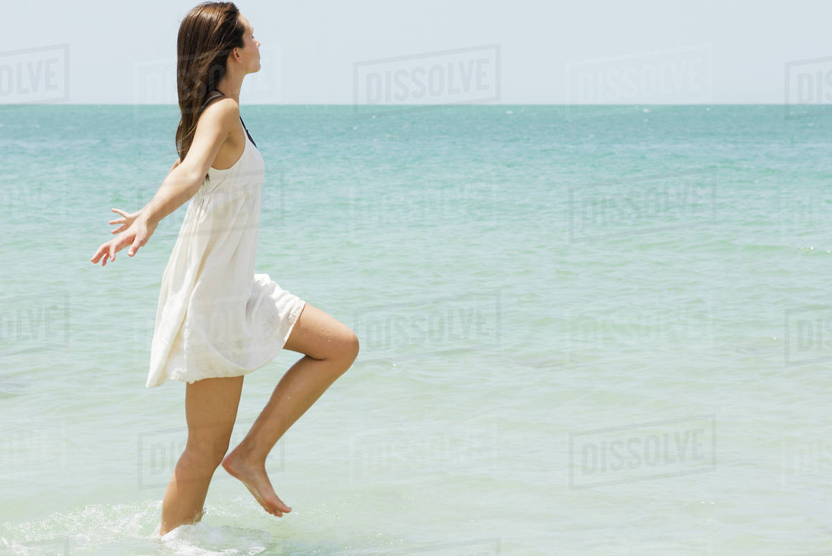 Young woman running in ocean, arms out, side view - Royalty-free Stock ...