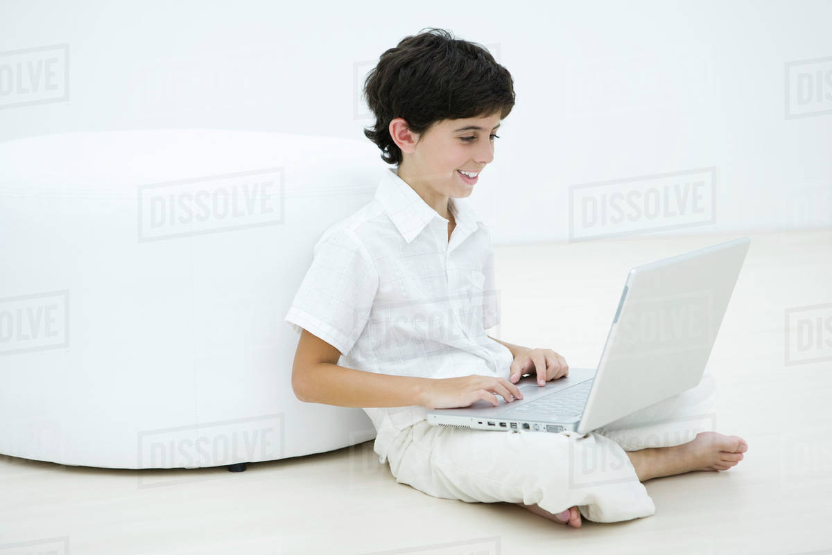 Boy sitting cross-legged on the floor using laptop - Royalty-free Stock ...