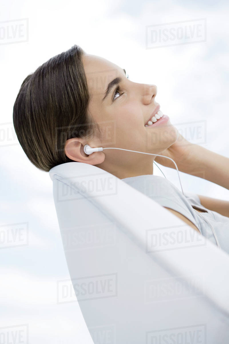 Female leaning back, listening to earphones, side view - Royalty-free ...
