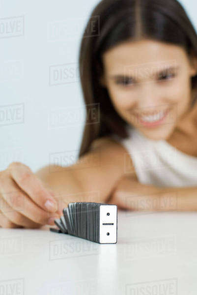 Woman setting off domino chain reaction, focus on foreground - Stock ...