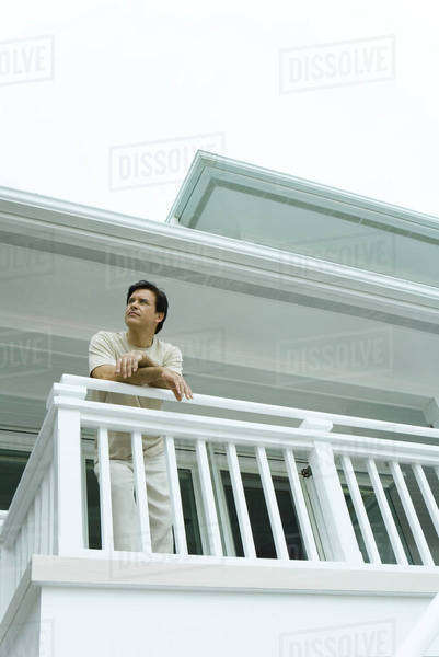 Man on balcony leaning against railing, looking away - Royalty-free ...
