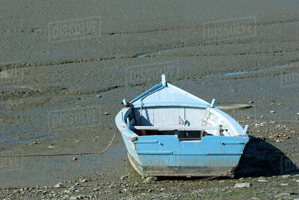 Rowboat stranded on mud flat - Stock Photo - Dissolve